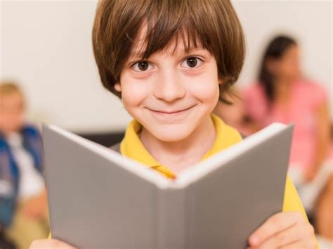 Маленький ребенок улыбается, держа книгу | Бесплатно Фото