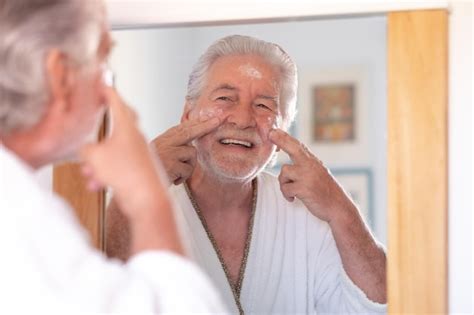 Premium Photo | Skin care handsome senior man applying cream at his ...