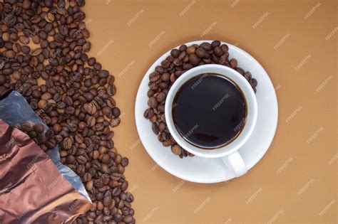 Белая чашка американо черного кофе без молока с кучей жареных кофейных ...