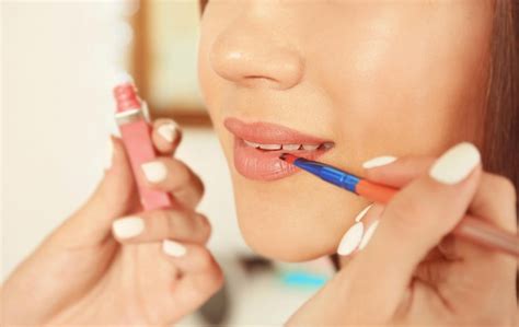 Premium Photo | Professional makeup artist applying lip gloss
