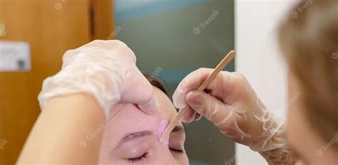 Premium Photo | A brow maker removes hair from a beautiful woman's face ...