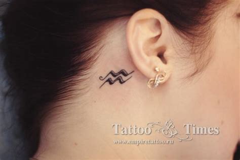 Маленькая тату знак воды за ухом - фото в салоне Tattoo Times