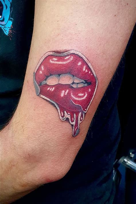 a man with a red lip tattoo on his arm