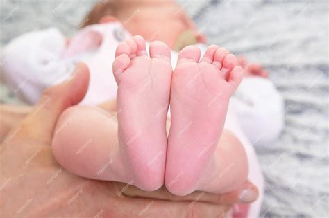 Ноги новорожденного ребенка в руках матери в семейной концепции ...