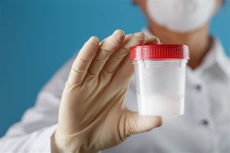 Premium Photo | A doctor's gloved hand holding a bottle of a container with a sperm sample for ...