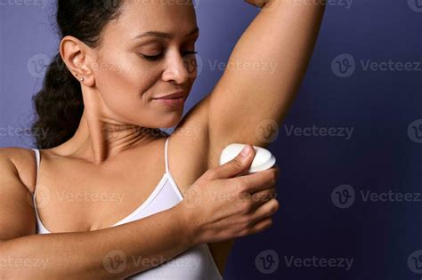 Close-up of a beautiful woman applying roll-on antiperspirant underarm. Protective sweating ...